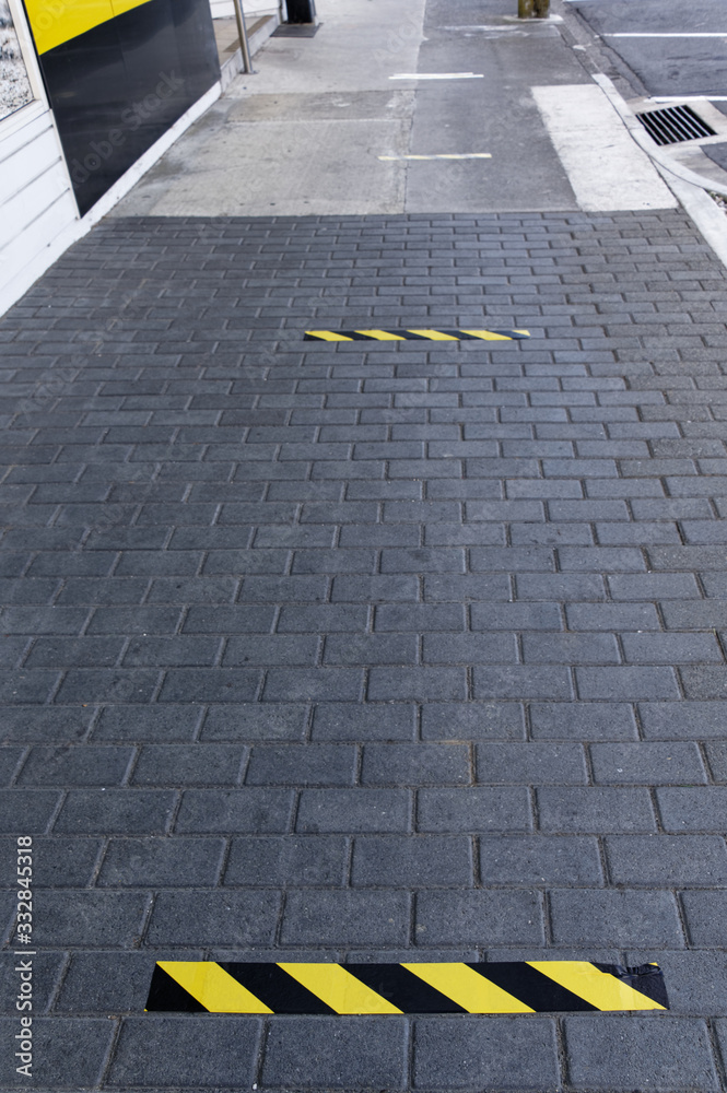 Yellow and black lines on the pavement mark the safe distance to stand ...