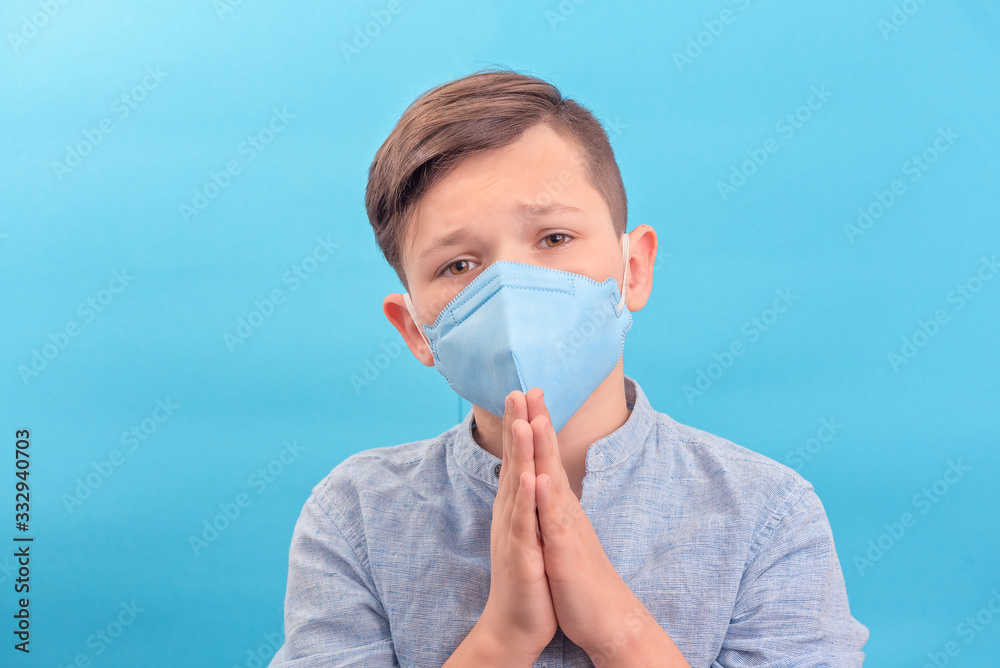Handsome brunette boy in medicine face mask is folded his hands in ...