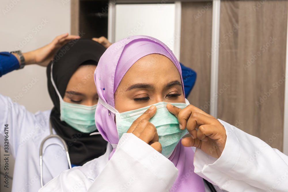 Muslim woman doctor secure her surgical mask by pinch the metal edge on ...