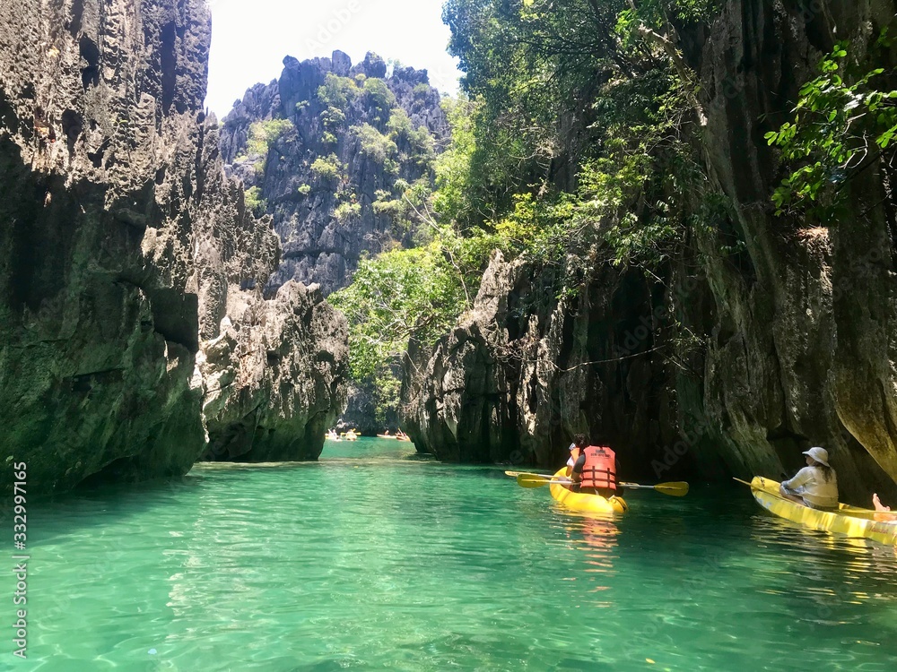 People in kayak in lagoon with green and blue water, with islands in ...
