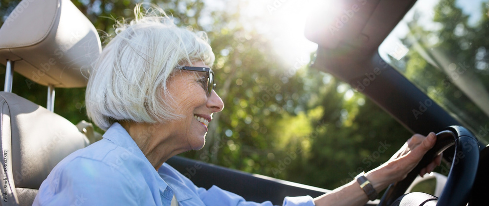 Relaxed older woman driving convertable car. Stock Photo | Adobe Stock