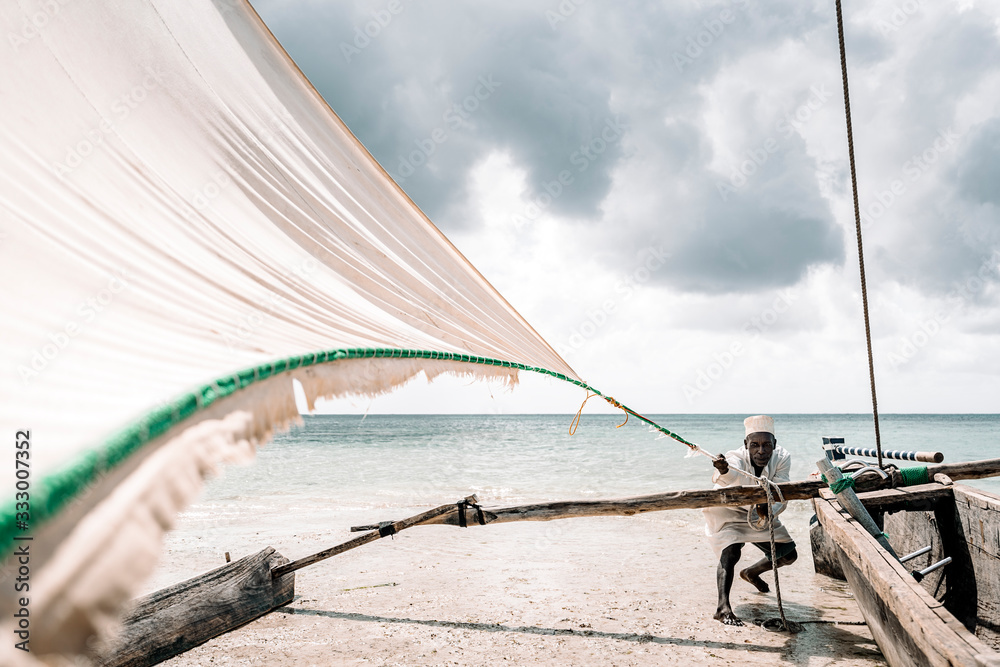 Fisherman pulling rope of sail on beach Stock Photo | Adobe Stock