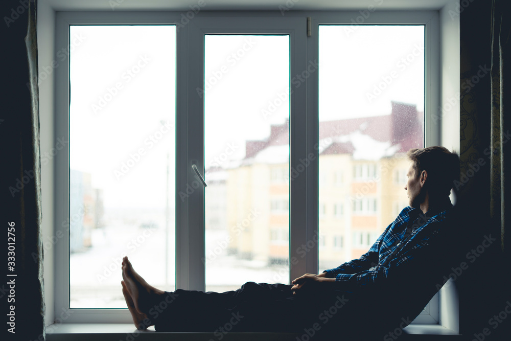 Sad Lonely Thoughtful Man Silhouette Sitting On A Window Windowsill And