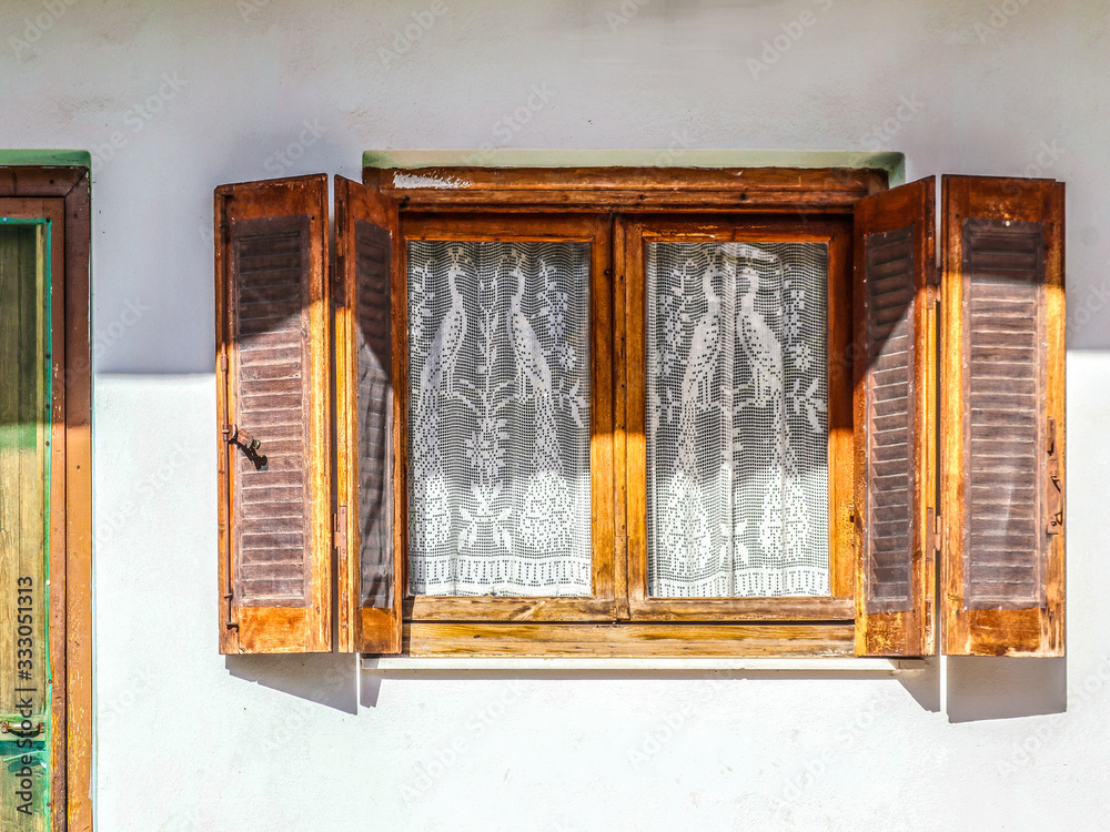 Old wooden window with open shutters on white stucco wall with insect ...