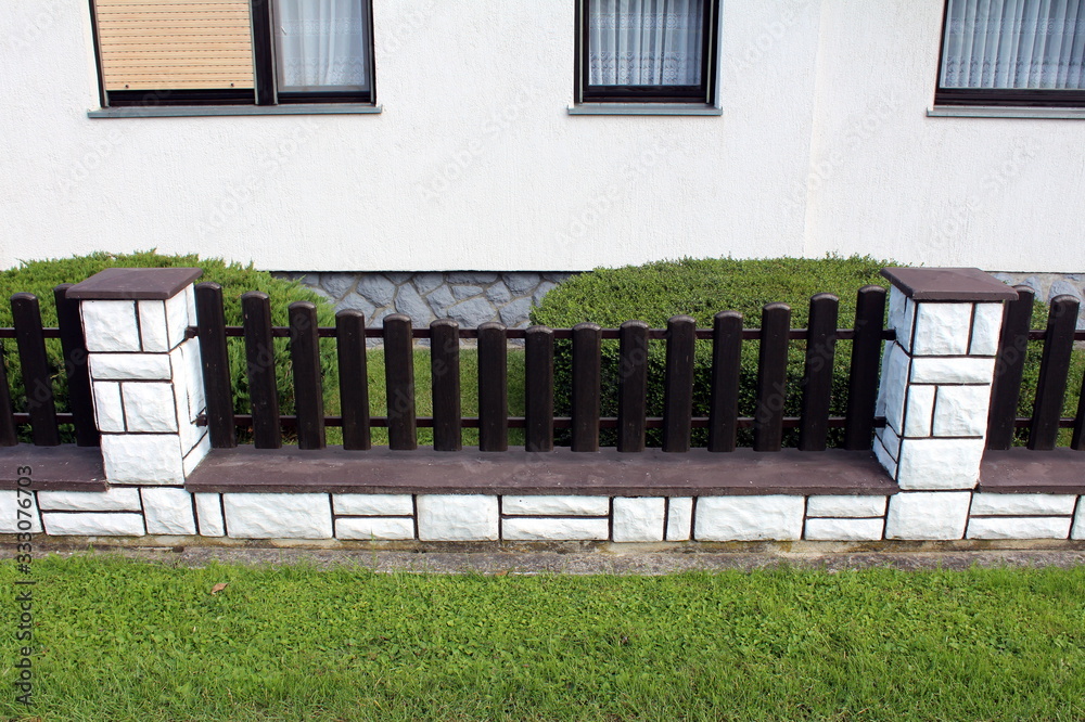 Dark brown wooden picket fence mounted on concrete foundation covered ...