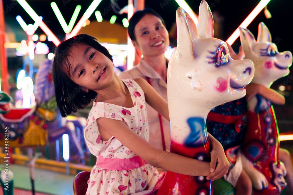 Kids playing background concept, child and mother playing carousel in ...