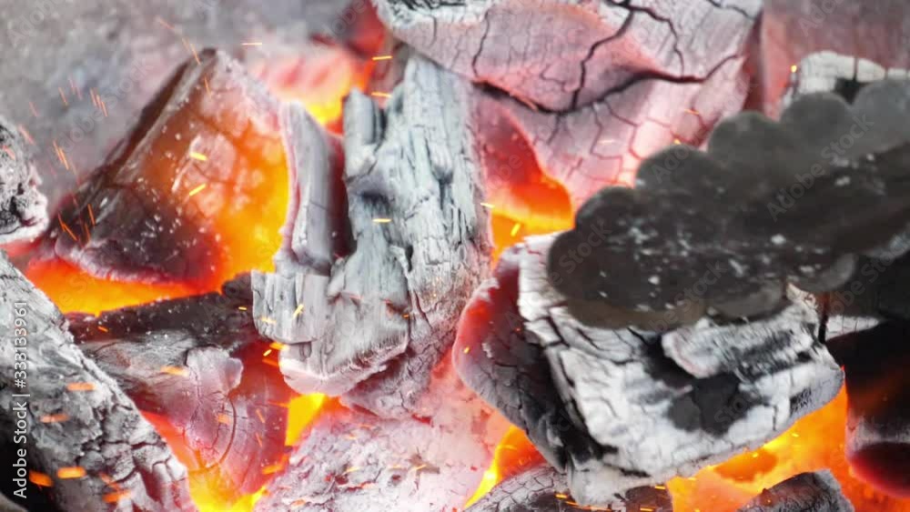 Slow motion speed closeup scene of tong dig on burning charcoal pile ...