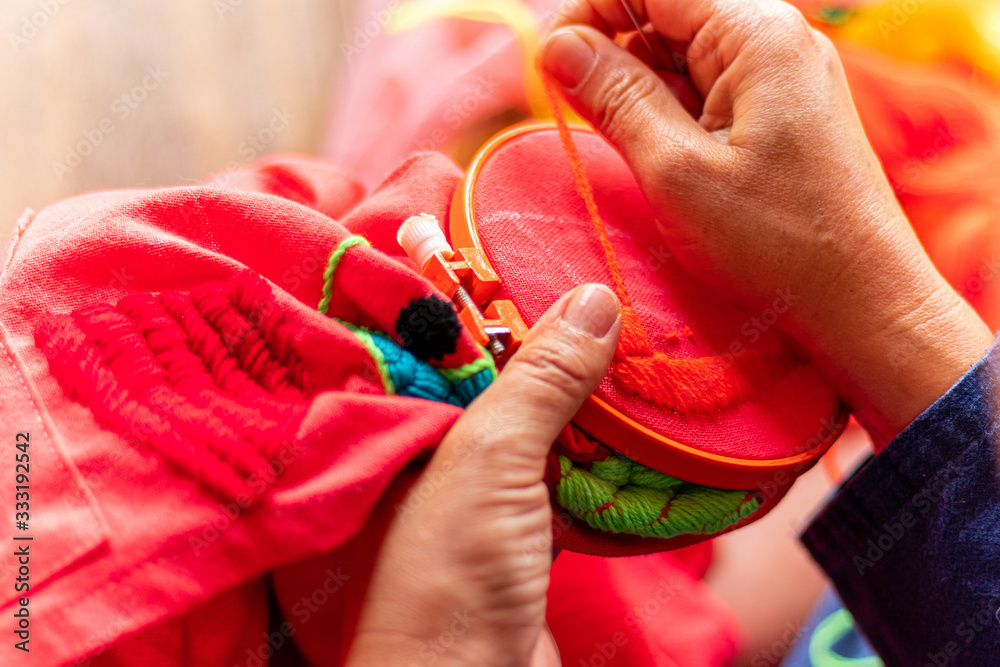 Asian woman's hand is embroidered with tribal native fabric. Sewing ...