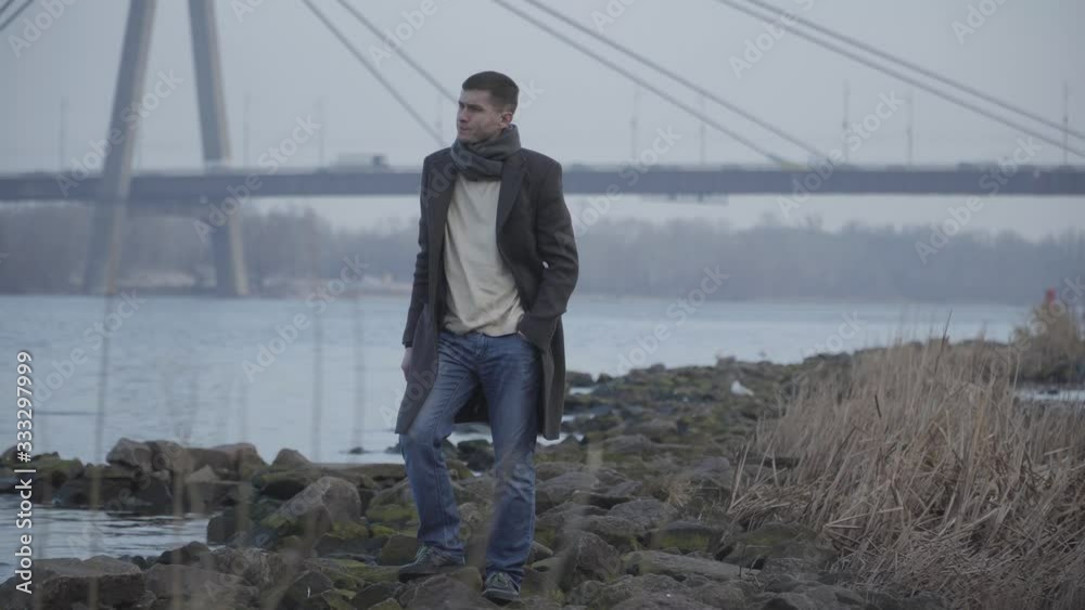 Portrait of stressed Caucasian man throwing away rock and walking along ...
