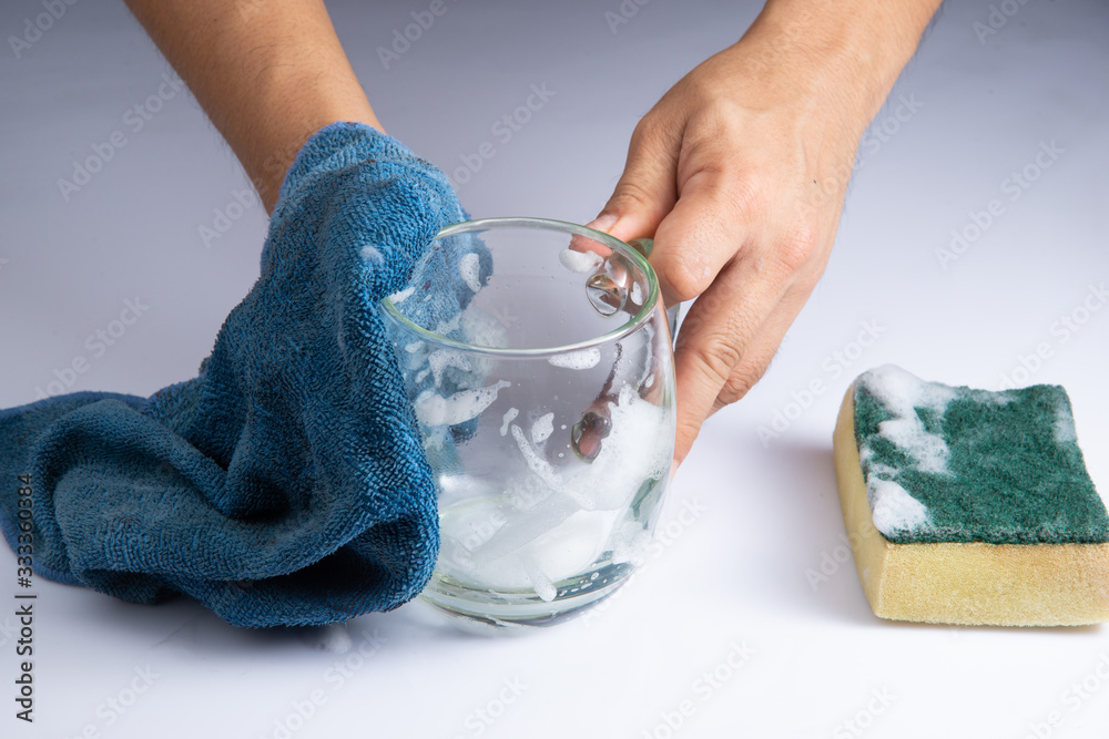 washing clear glass by bare hand and blue rag sponge foam on white ...