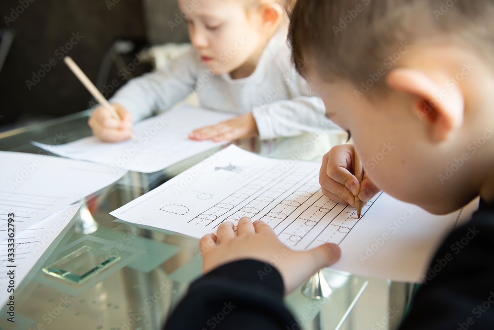 Schoolboy and schoolgirl writing letters. Close-up pencil in the hand ...