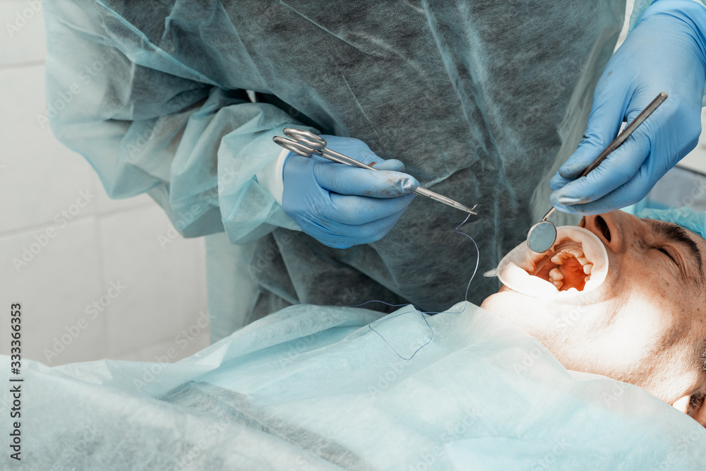 Patient and dentist during implant placement operation. Real operation ...