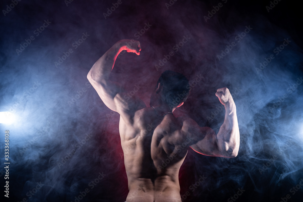 Muscular man showing muscles isolated on the black background. Concept ...