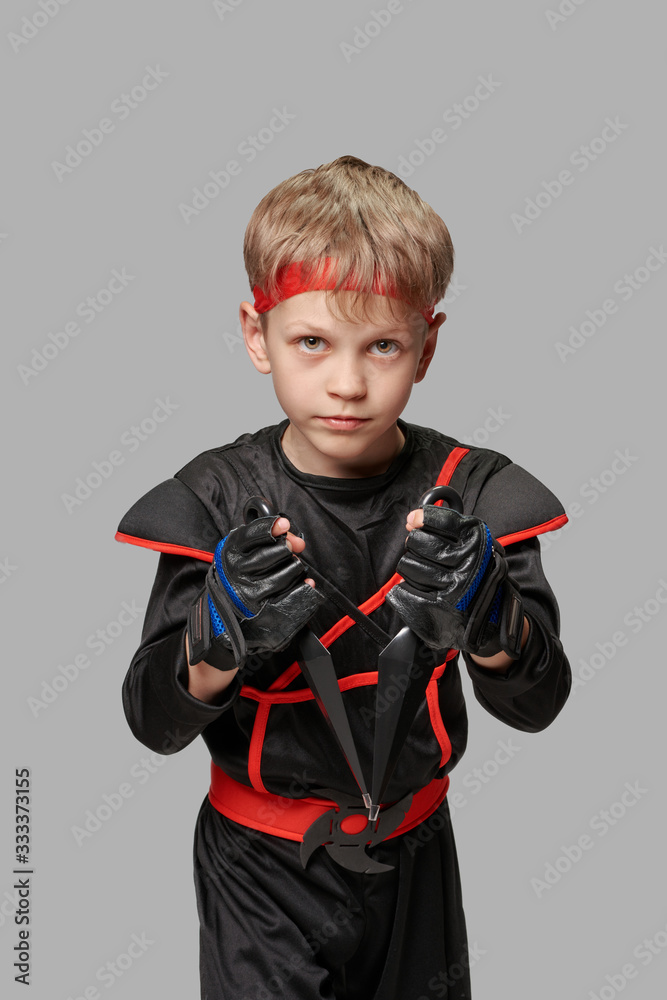 Young boy dressed as ninja posing with kunai on gray background Stock ...