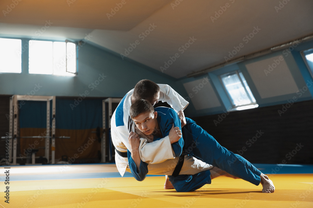 Two young judo caucasian fighters in white and blue kimono with black ...