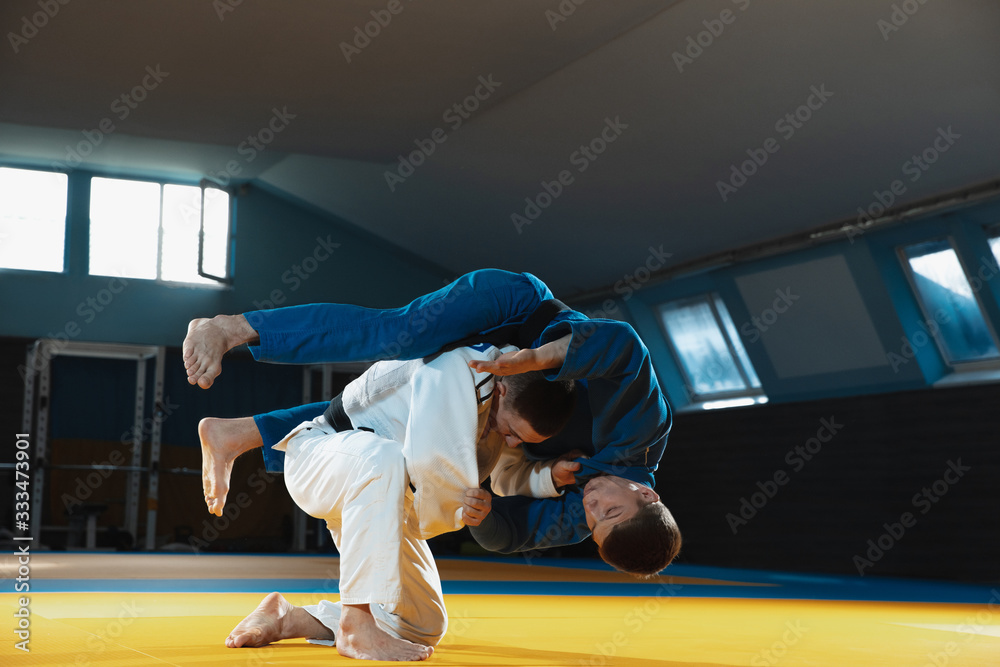 Two young judo caucasian fighters in white and blue kimono with black ...