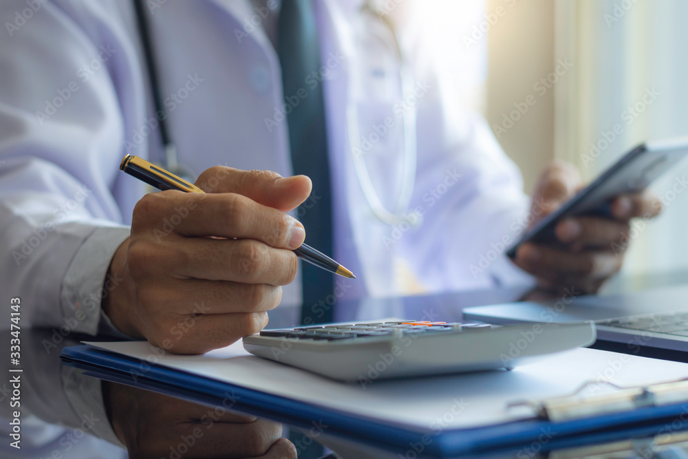 Male doctor hand hold pen, using calculator for calculate about medical ...