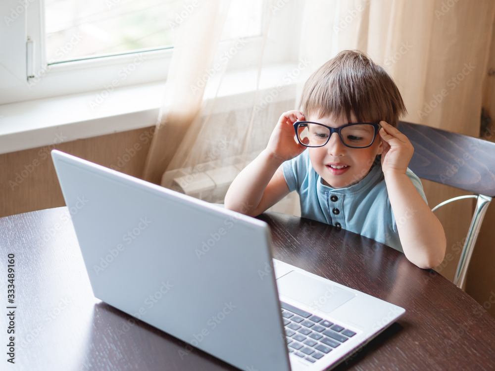 Curious toddler boy explores the laptop and staring on screen through ...