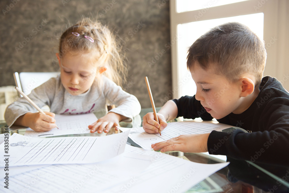 Schoolboy and schoolgirl writing letters. Close-up pencil in the hand ...