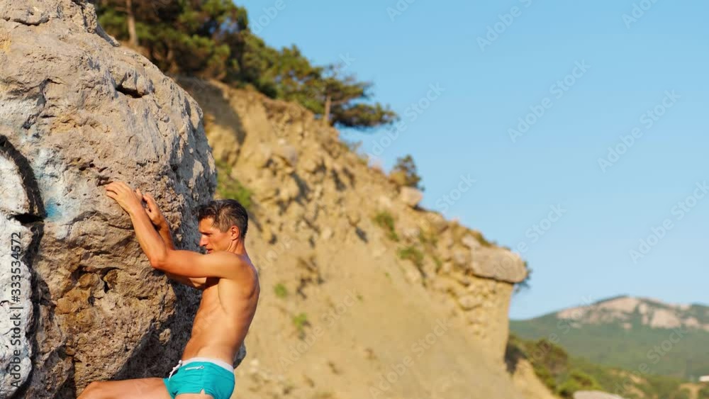 Video Stock tanned athletic man in swimming trunks climbs bare feet on ...