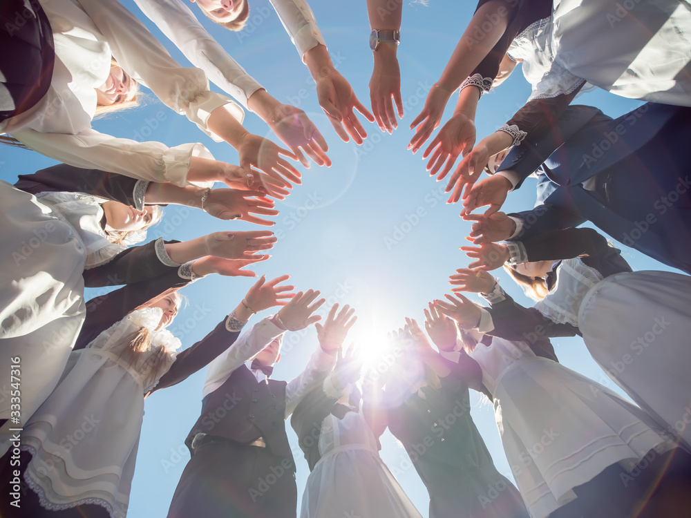 Students graduates make the shape of a circle from the palms of their ...