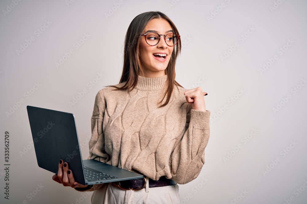 Young beautiful brunette woman working using laptop over isolated white ...