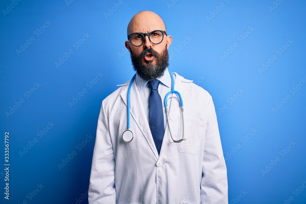 Handsome bald doctor man with beard wearing glasses and stethoscope ...