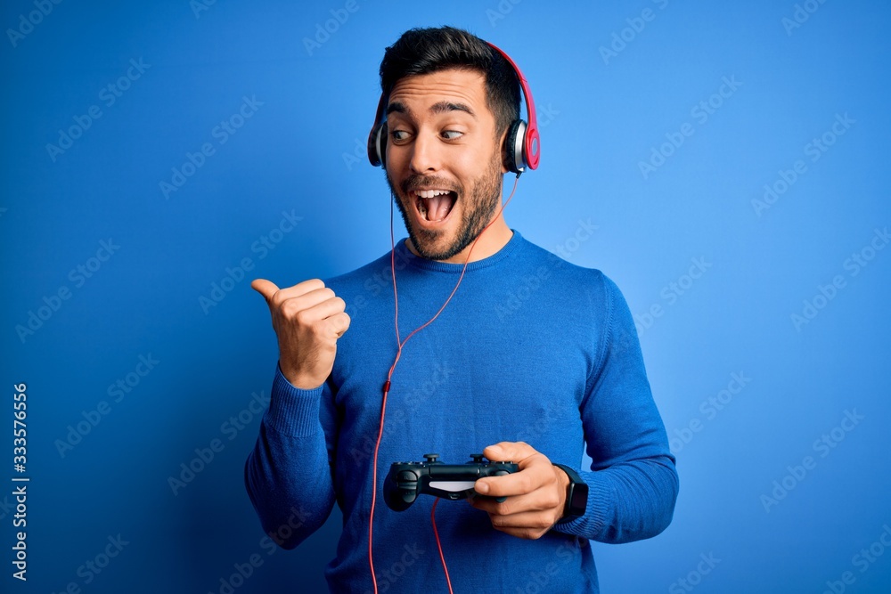 Young handsome gamer man with beard playing video game using joystick ...