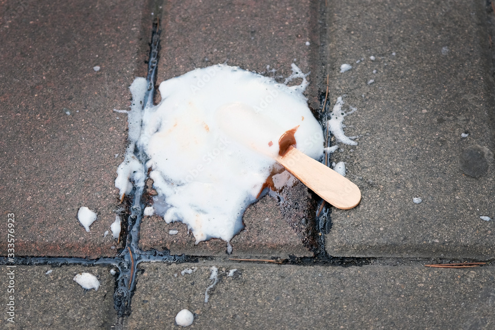 Melted ice cream on a stick on the sidewalk. ice cream bar fell to the ...