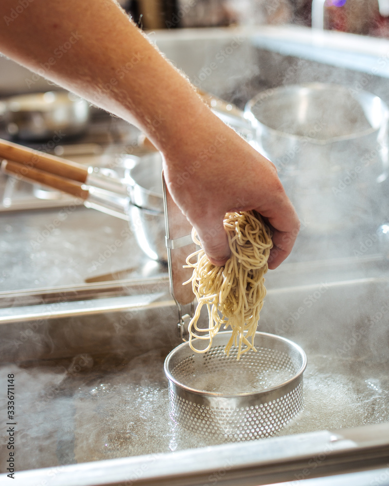 Chef cooking ramen noodles in the restaurant kitchen, side view ...