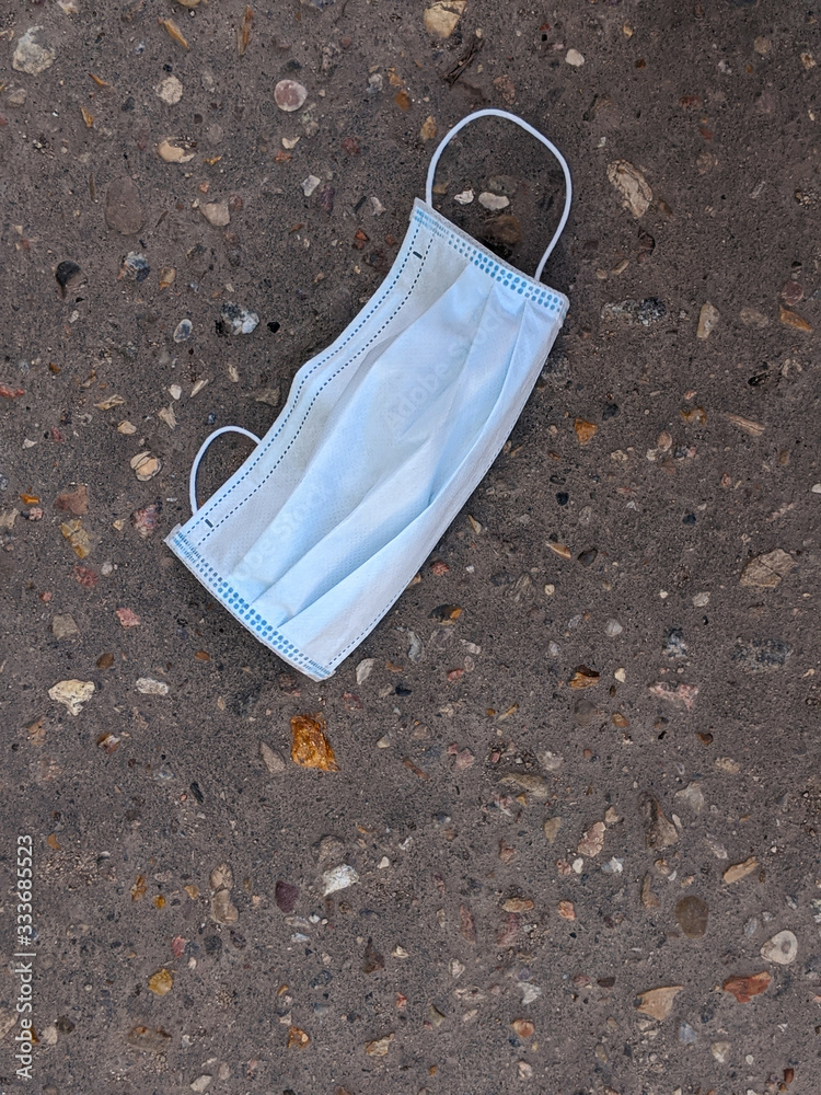 Discarded surgical mask or face mask abandoned on the ground. One image ...