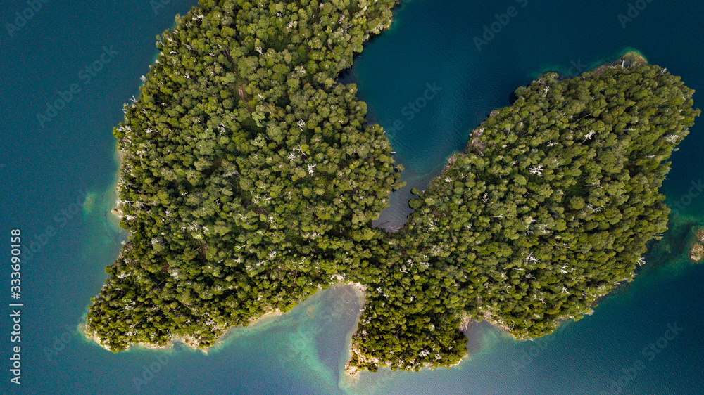 Aerial top view of lunge-shaped island on dark blue waters lake in ...
