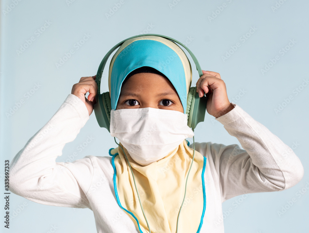 Muslim girl with hijab wearing surgical mask listening to music on her ...