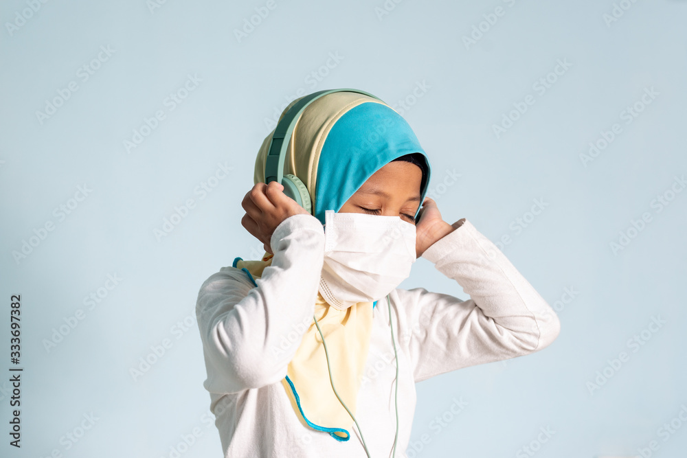 Muslim girl with hijab wearing surgical mask listening to music on her ...