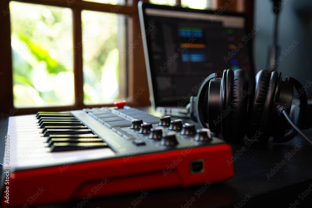 Midi keybard in a music producer home studio, desk with headphones and ...