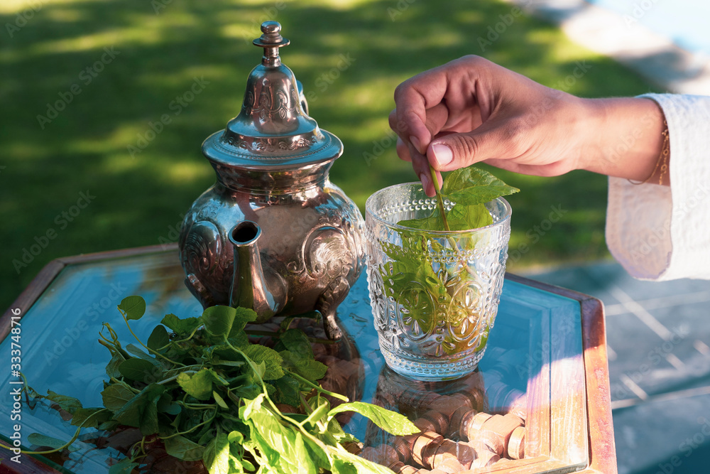 Moroccan green herbal tea poured with silver teapot in traditional ways ...