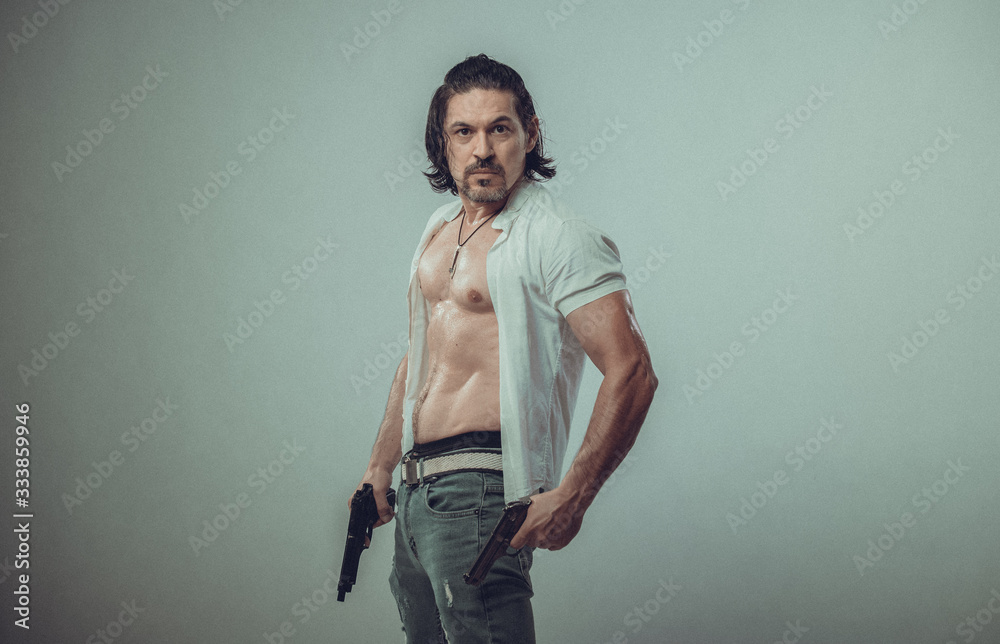 sexy muscular body model portrait of a young man holding a gun in his ...
