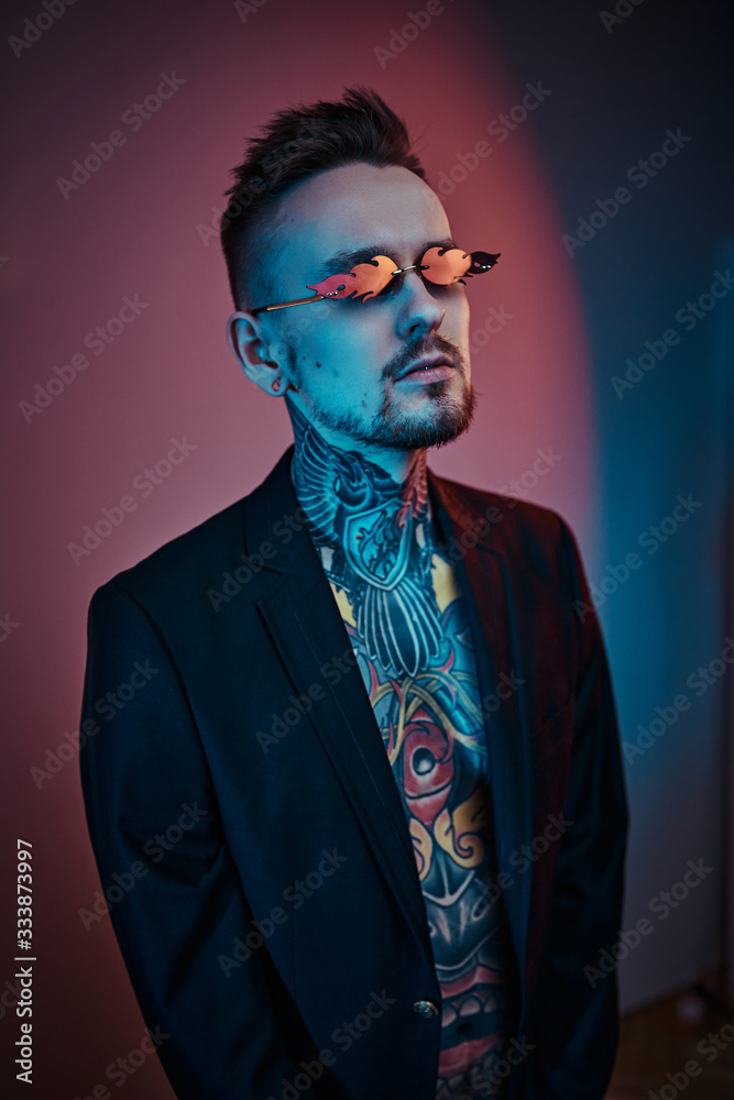 Cool and rebellious male model posing in a neon studio wearing a black ...