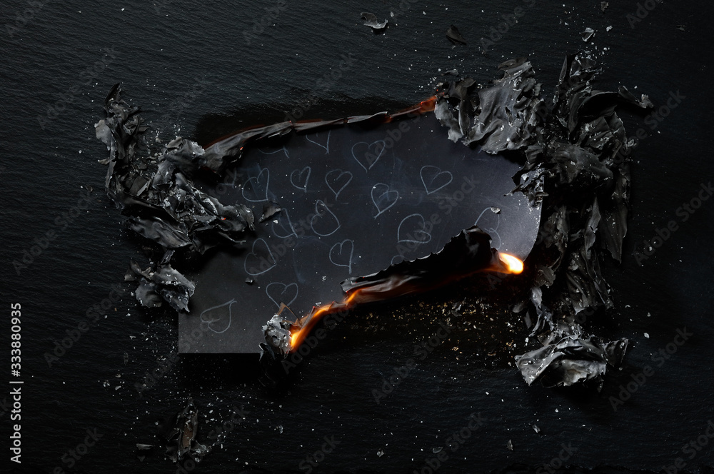 Burning piece of black paper with the symbol "Hearts " or "Love" on a ...