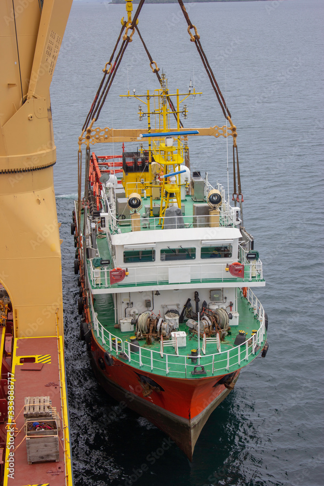 a scientific ship is loaded onto a deck of a heavy lift vessel by ...