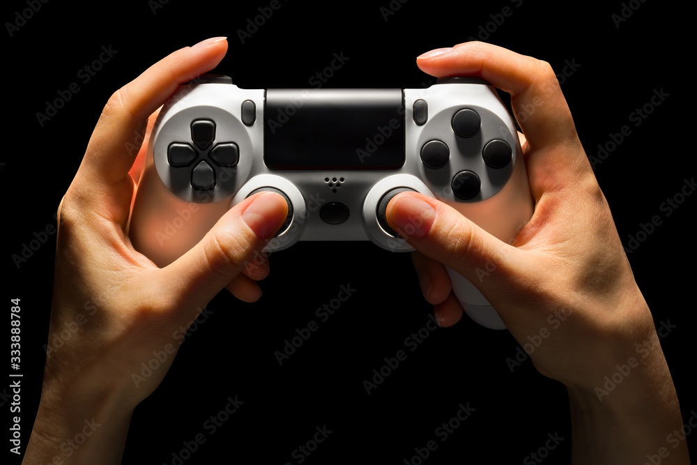 Hyman hands holding white video game gamepad isolated on a black ...
