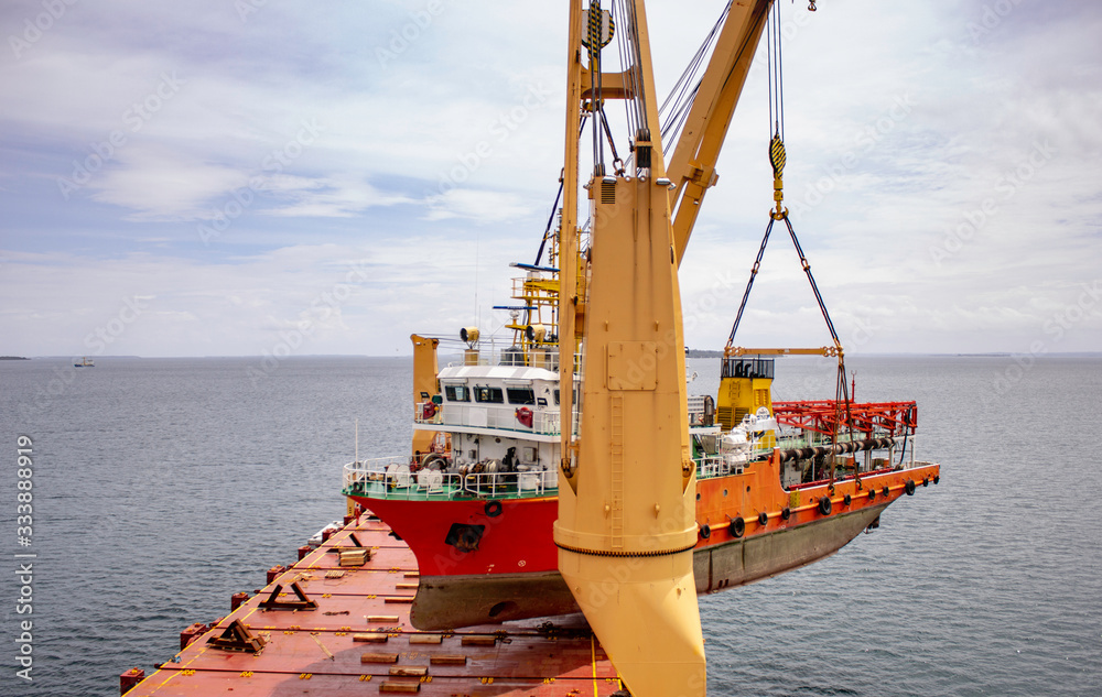 a scientific ship is loaded onto a deck of a heavy lift vessel by ...