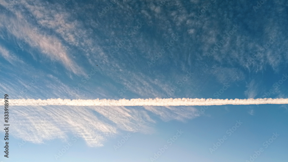 Pattern of airplane trails cutting blue sky in half. Airplane leaving ...