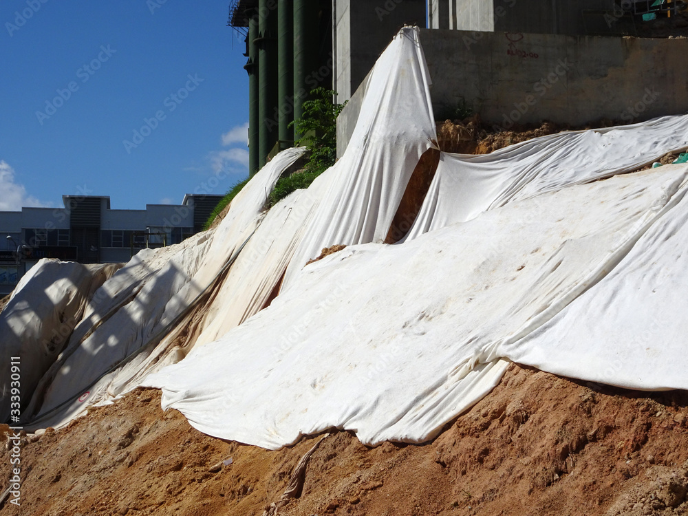 The geotextile fabric is spread over the surface of the slope to ...