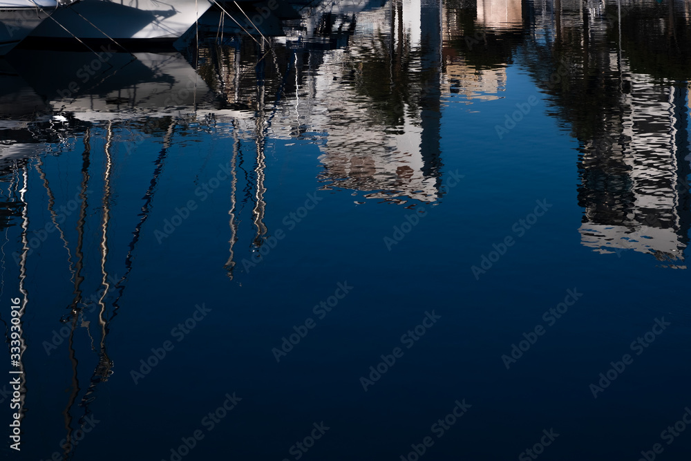 Smooth wavy water with reflection. Sky, buildings and yacht masts ...