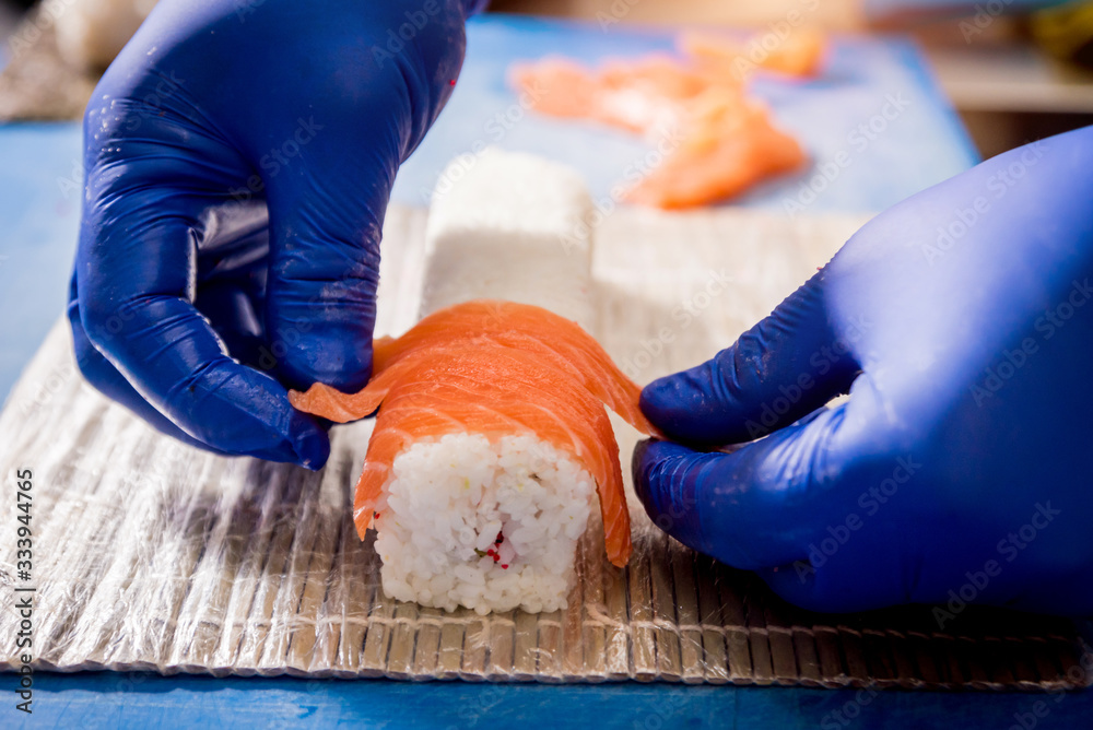 Process of making sushi and rolls at restaurant kitchen. Chefs hands ...