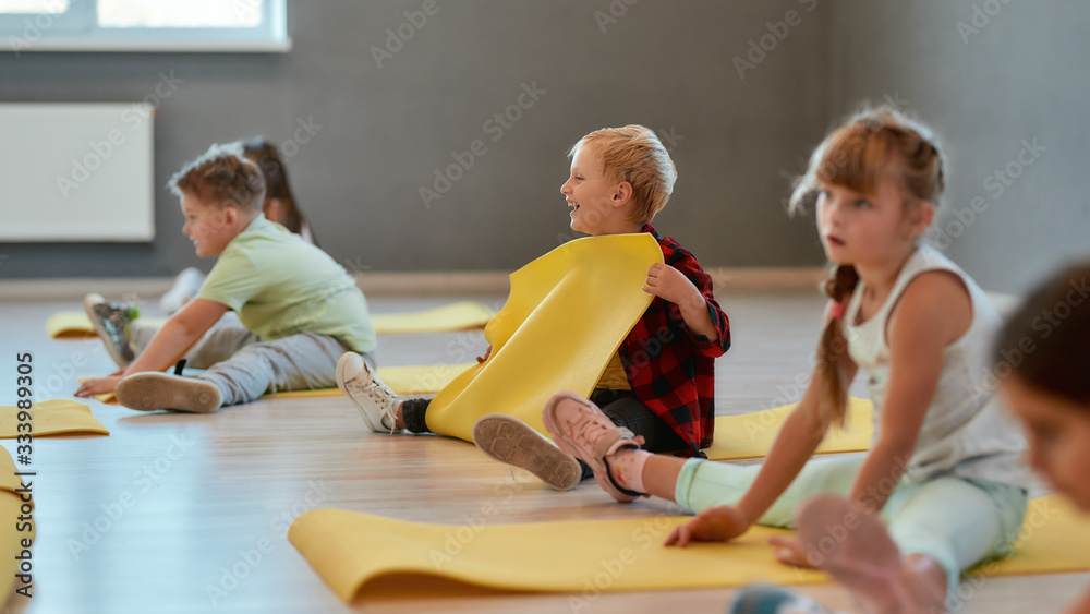 Group of children sitting on the floor and doing stretching exercises ...