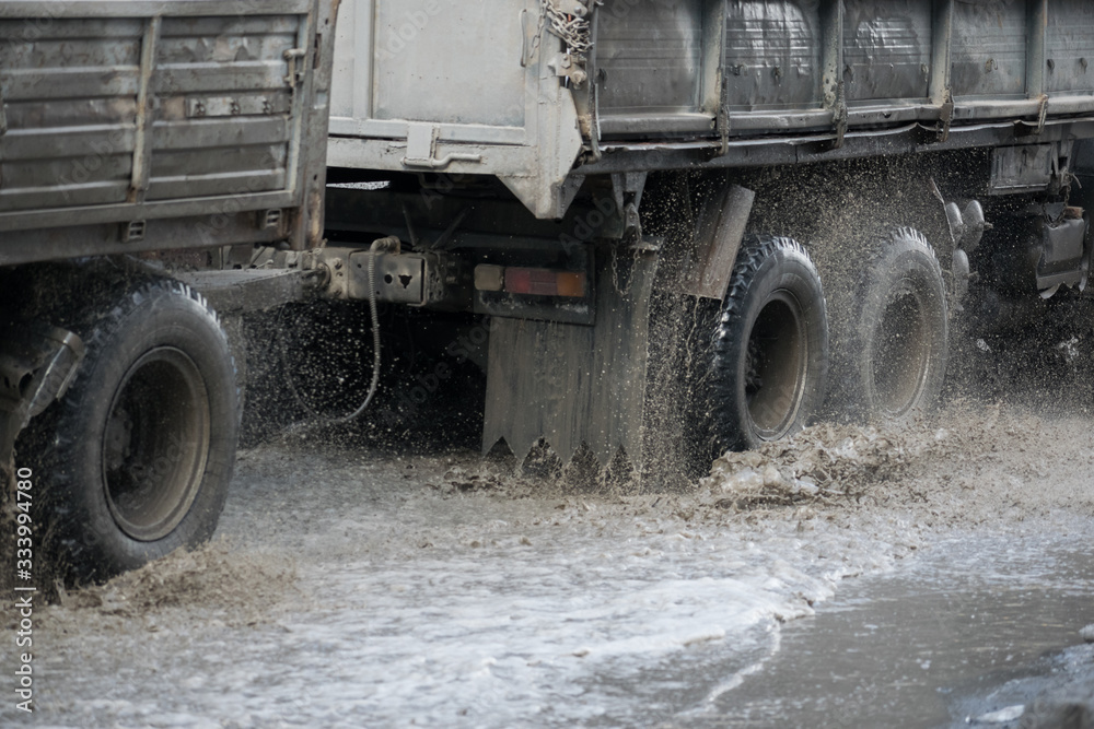 Car motion through big puddle of water splashes from the wheels on the ...