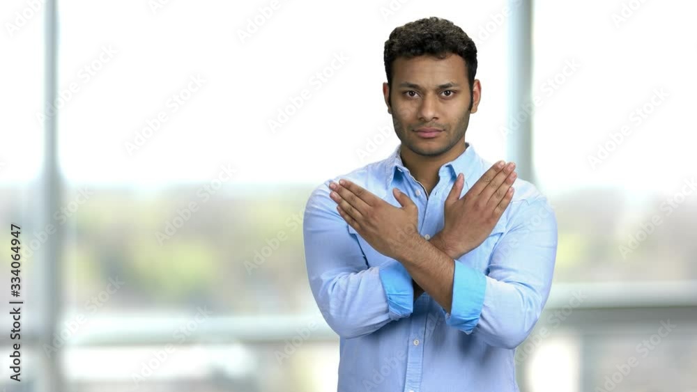 Serious young indian man showing cross stop gesture with arms. Portrait ...