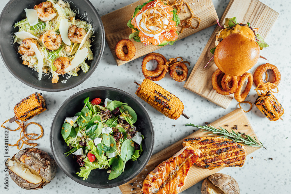 Colorful Dinner table with grilled meat, salads and burger. Restaurant ...